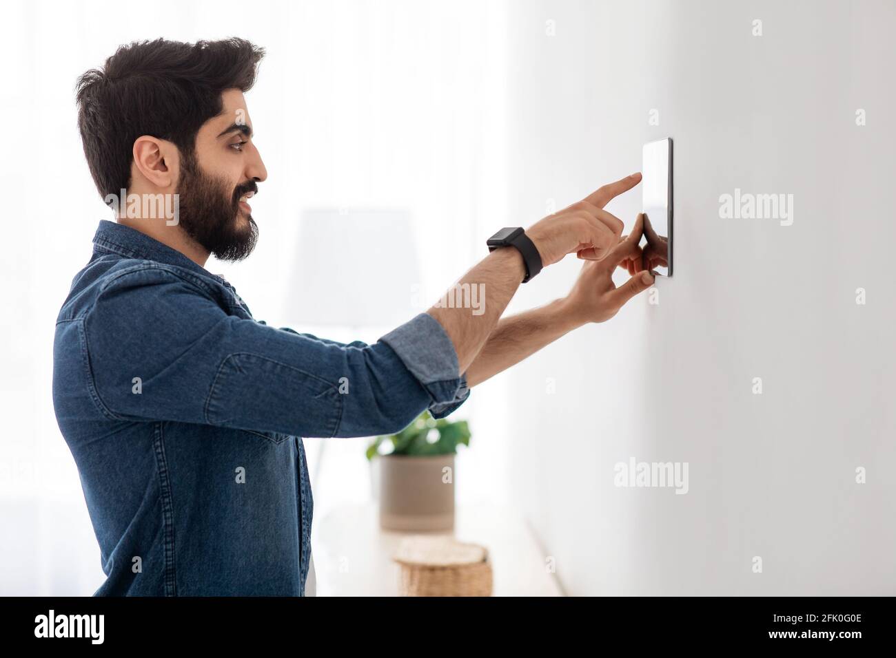 Smart home concept. Arab man using control system on digital tablet on ...