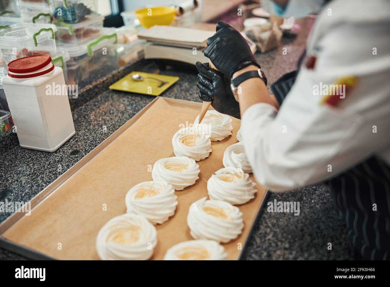 Focused pastry chef putting icing on top of meringues Stock Photo - Alamy