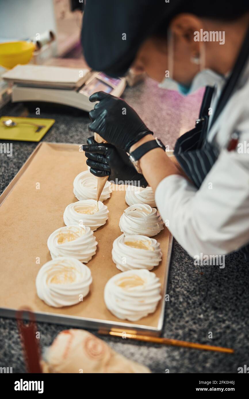 Dedicated pastry chef decorating meringues with icing Stock Photo - Alamy