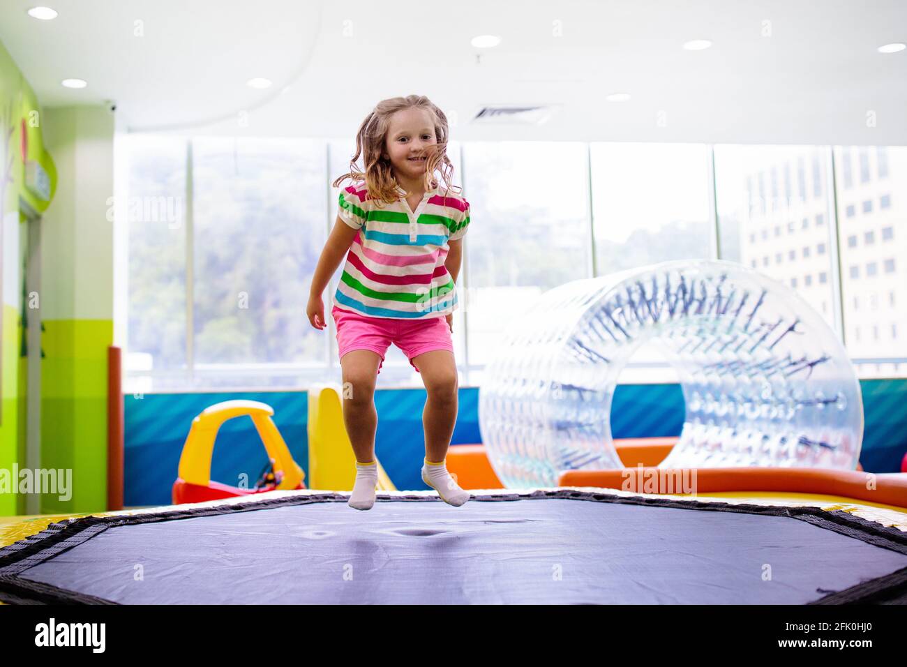 Child jumping on colorful playground trampoline. Kids jump in ...