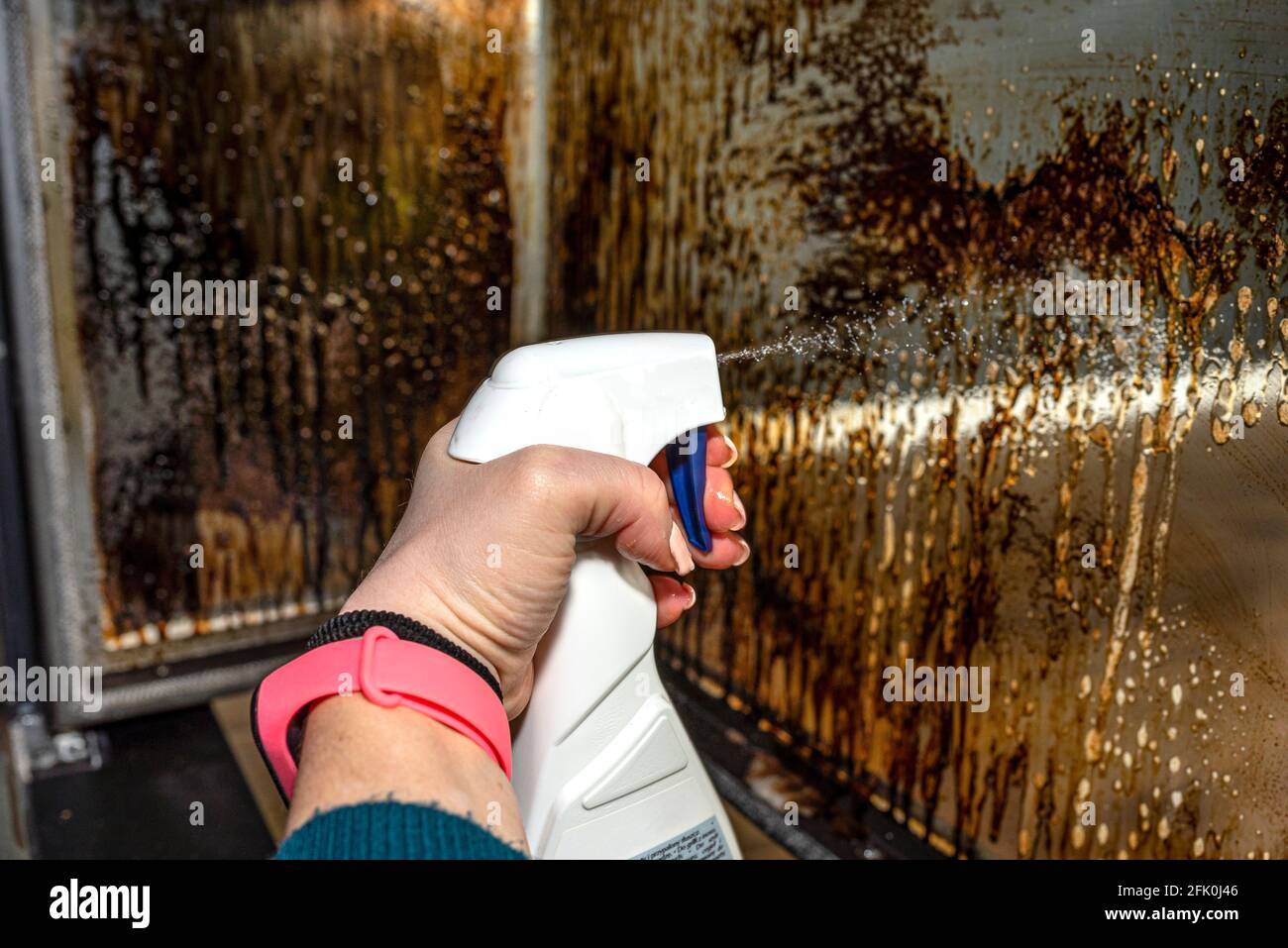 A woman spraying a corner glass pane covered in soot in a modern ...