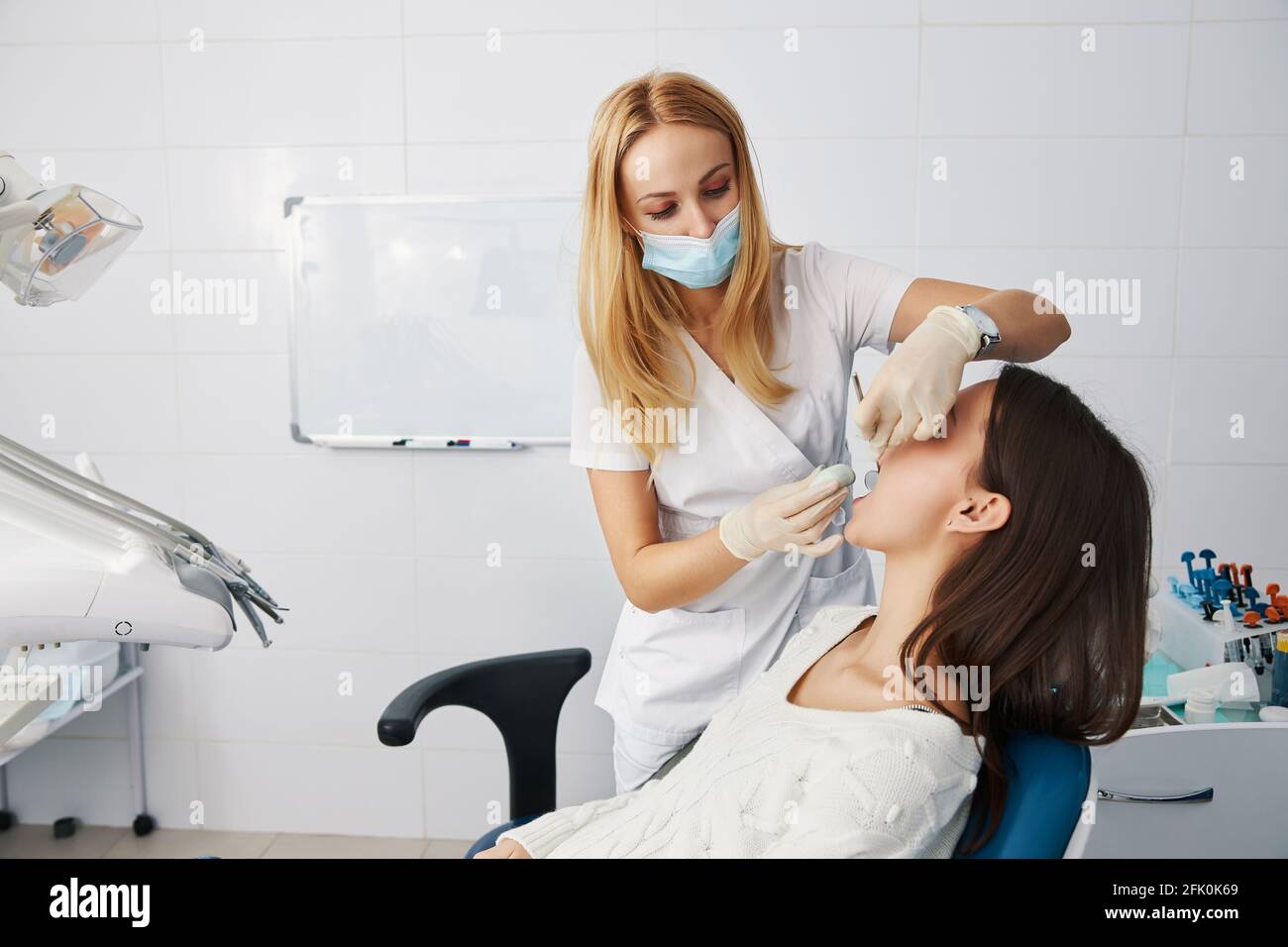 Dentist putting putty stone into patient mouth for dental impression ...