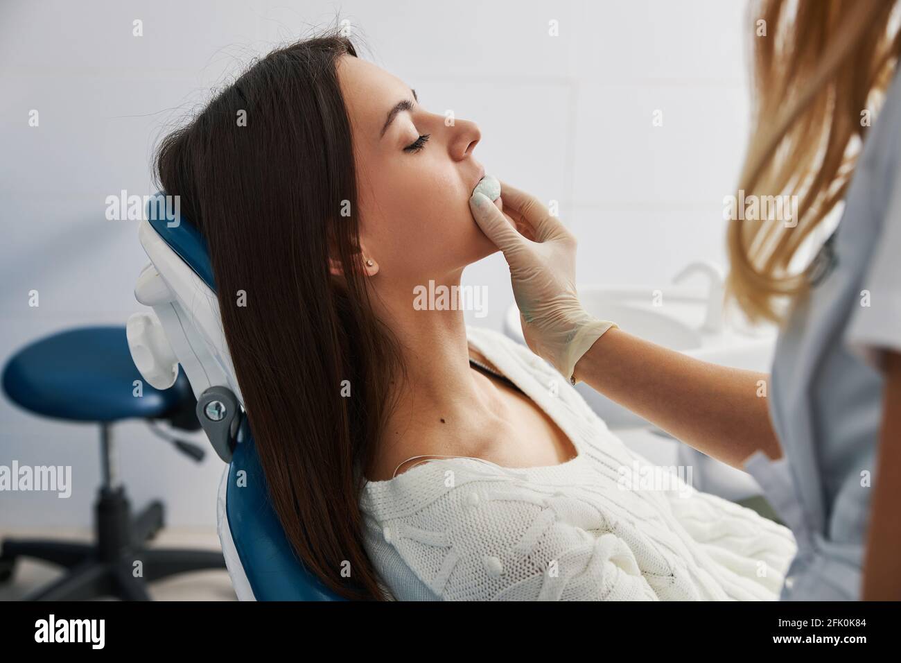 Dental office employee taking out teeth impression from lady mouth ...