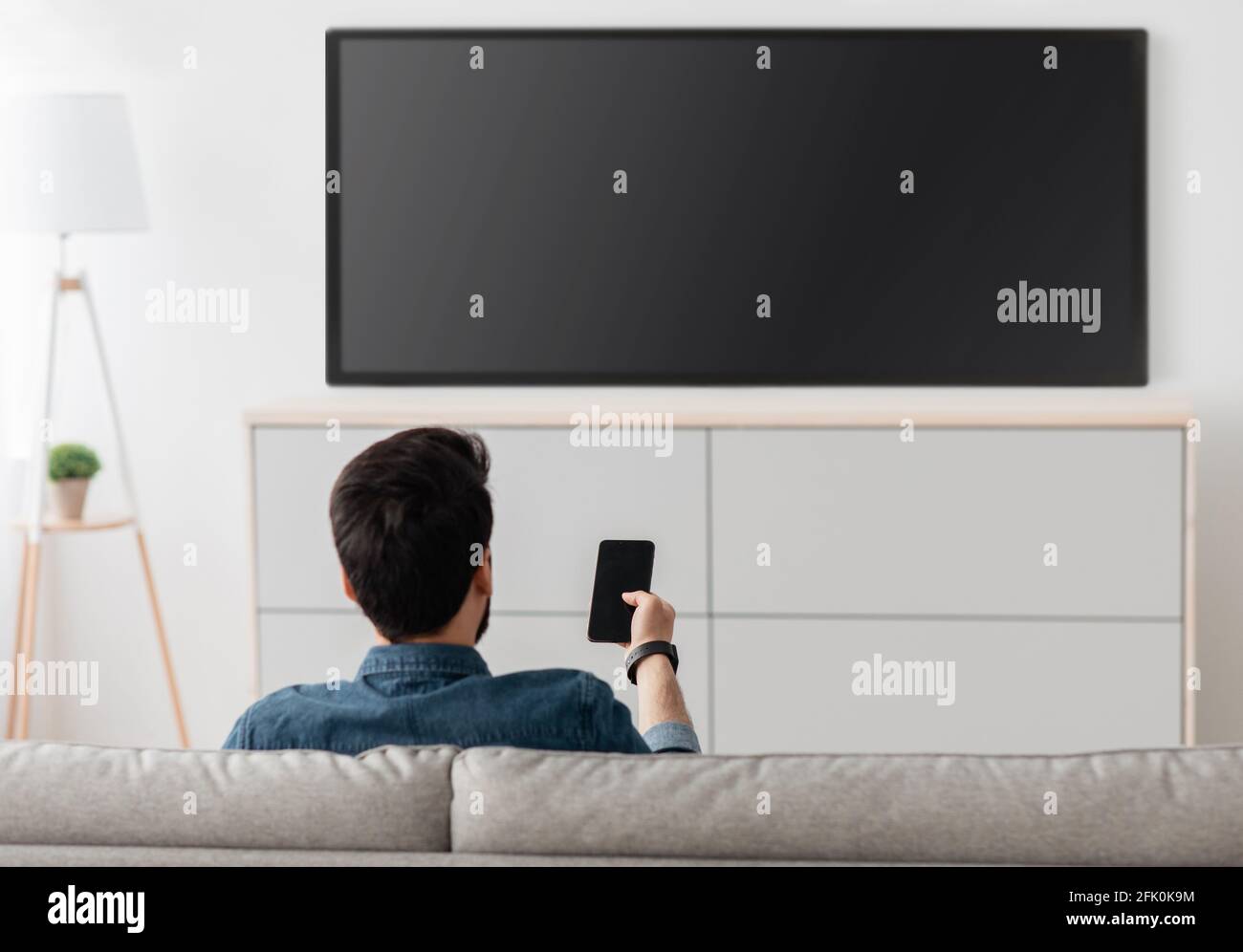 Modern gadgets. Unrecognizable man with smartphone connected to TV ...