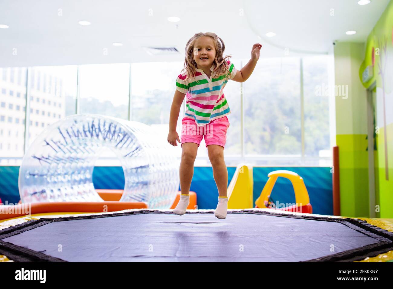 Child jumping on colorful playground trampoline. Kids jump in ...