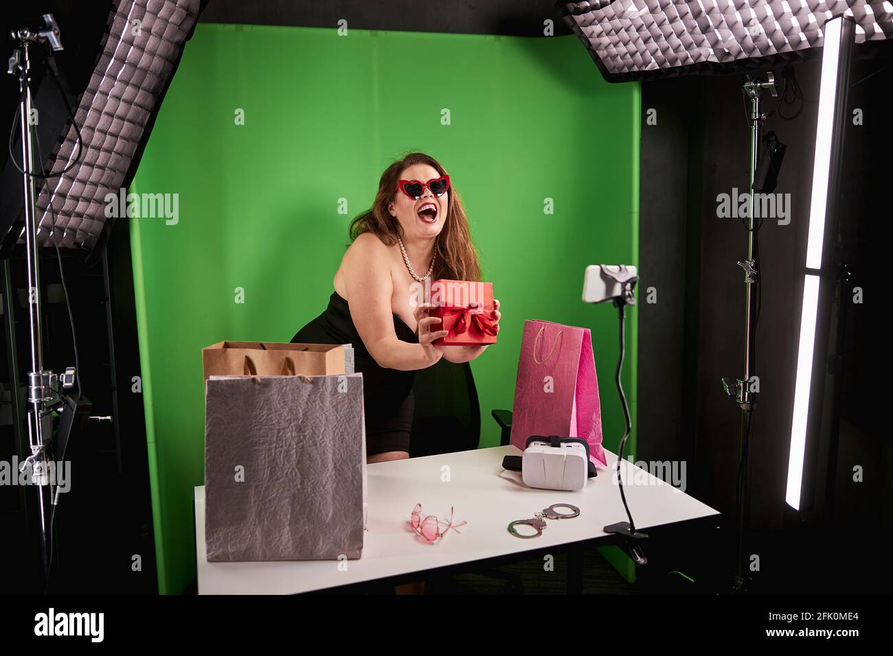 Laughing lady showing wrapped present to camera Stock Photo - Alamy
