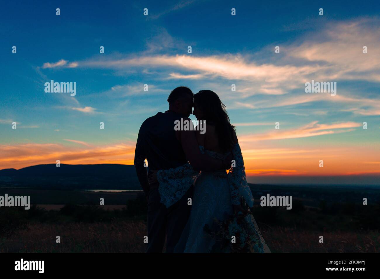Silhouette of a couple hugging and kissing at sunset against the ...