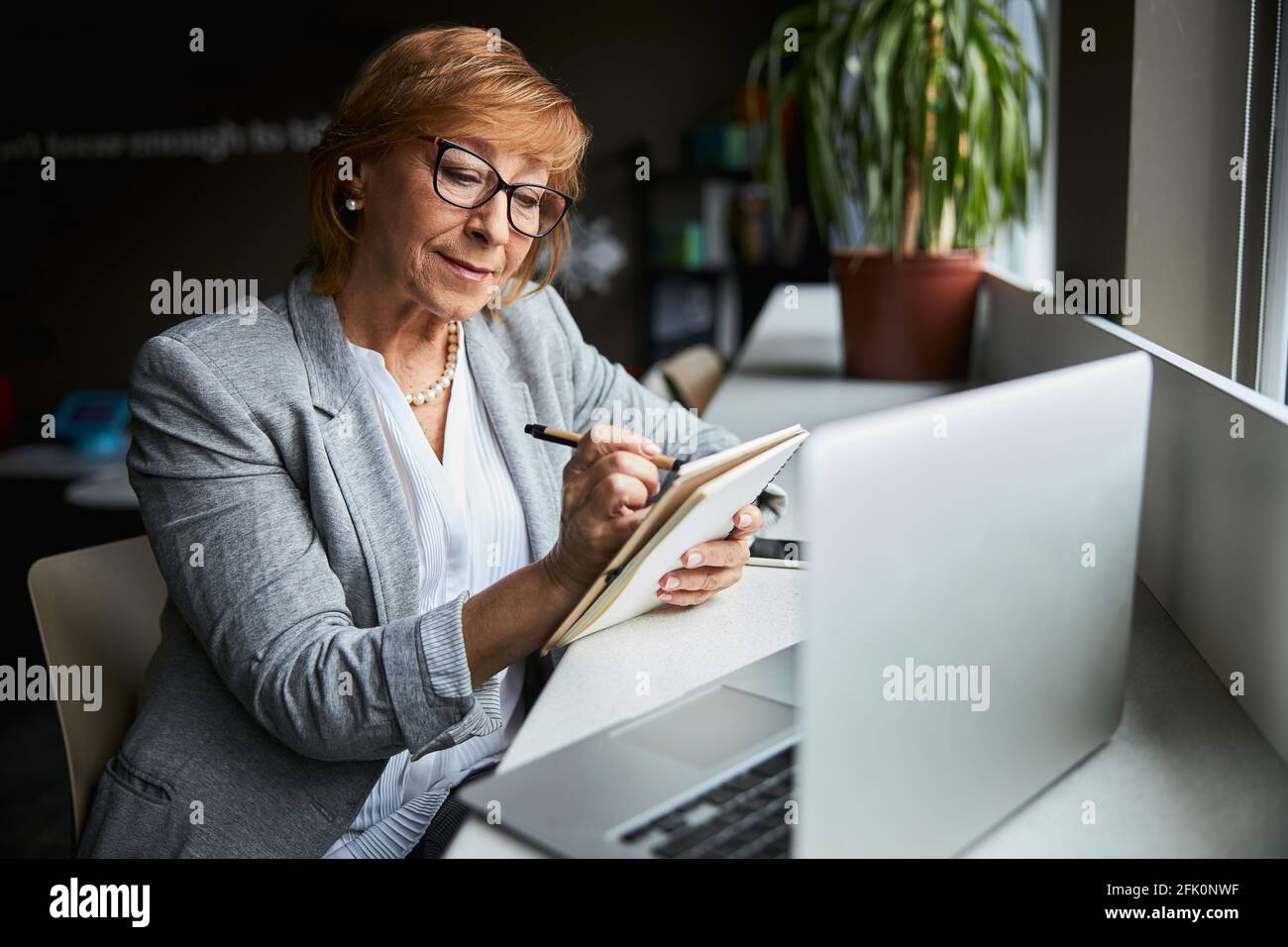 Positive delighted female person writing important notices Stock Photo ...