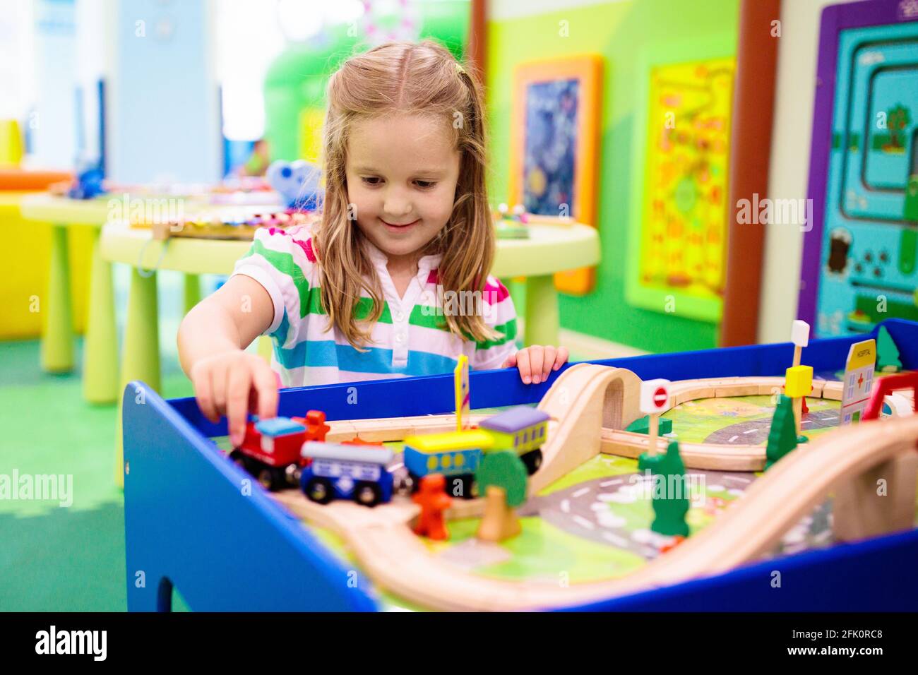 Kids play toy railroad. Little girl with wooden trains in indoor ...