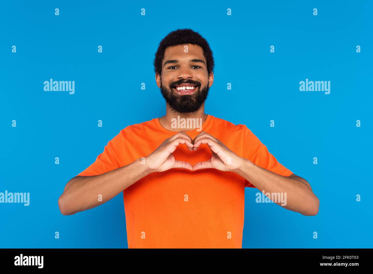 happy and bearded african american man showing heart sign with hands ...