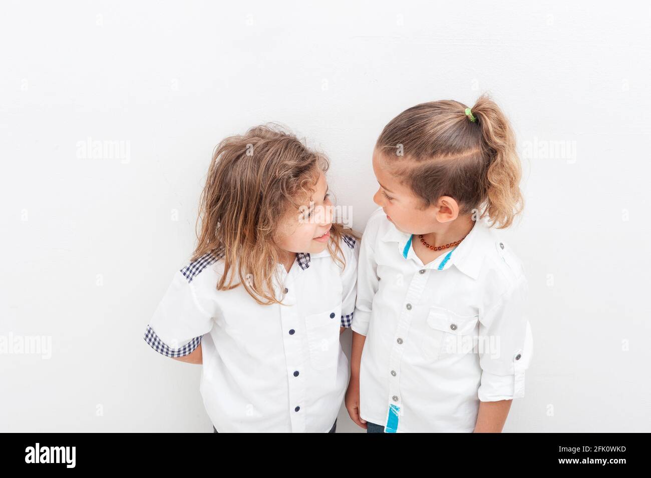 Two multiethnic boys brothers, with long blond hair look each other in ...