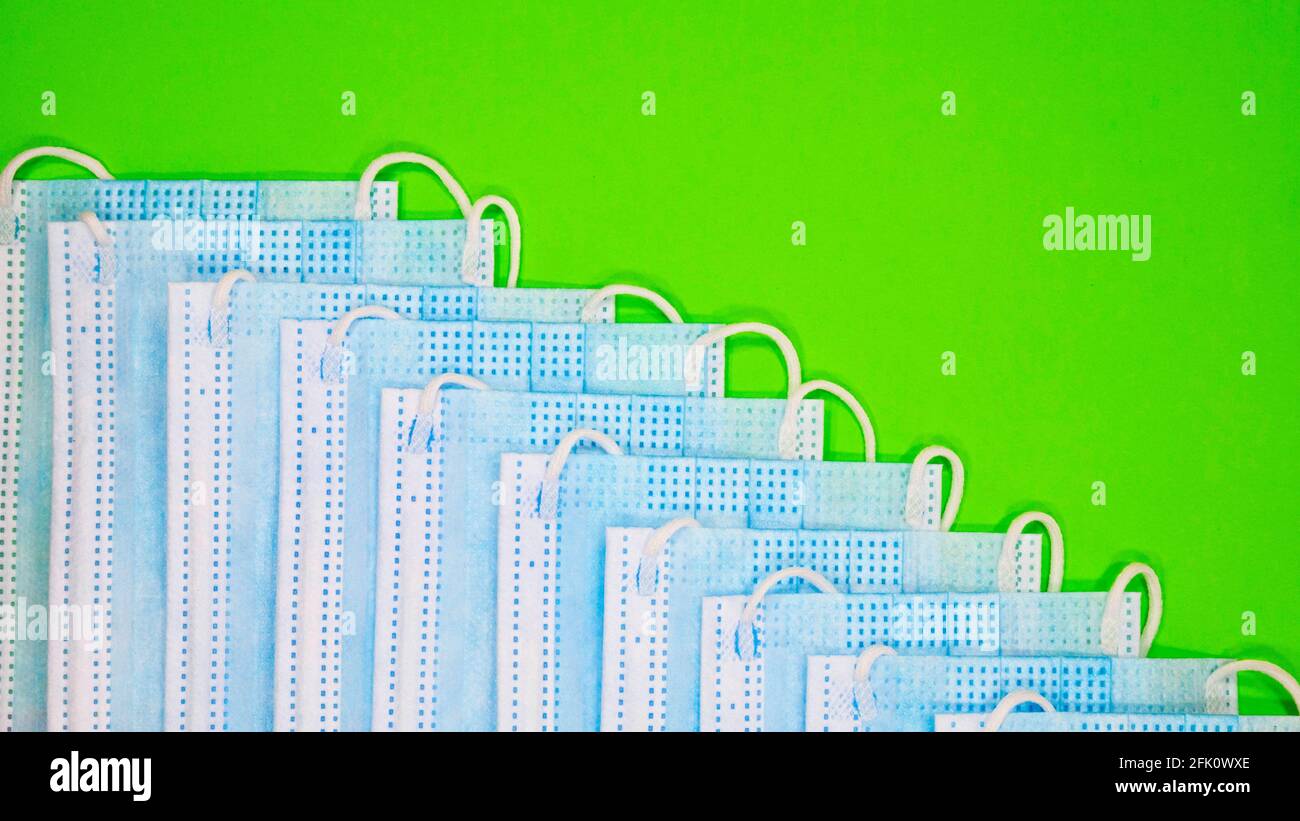 Blue medical masks on a green background. Negative space or copy space ...