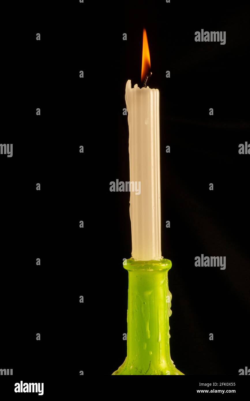 Single candle in green bottle on black background Stock Photo - Alamy