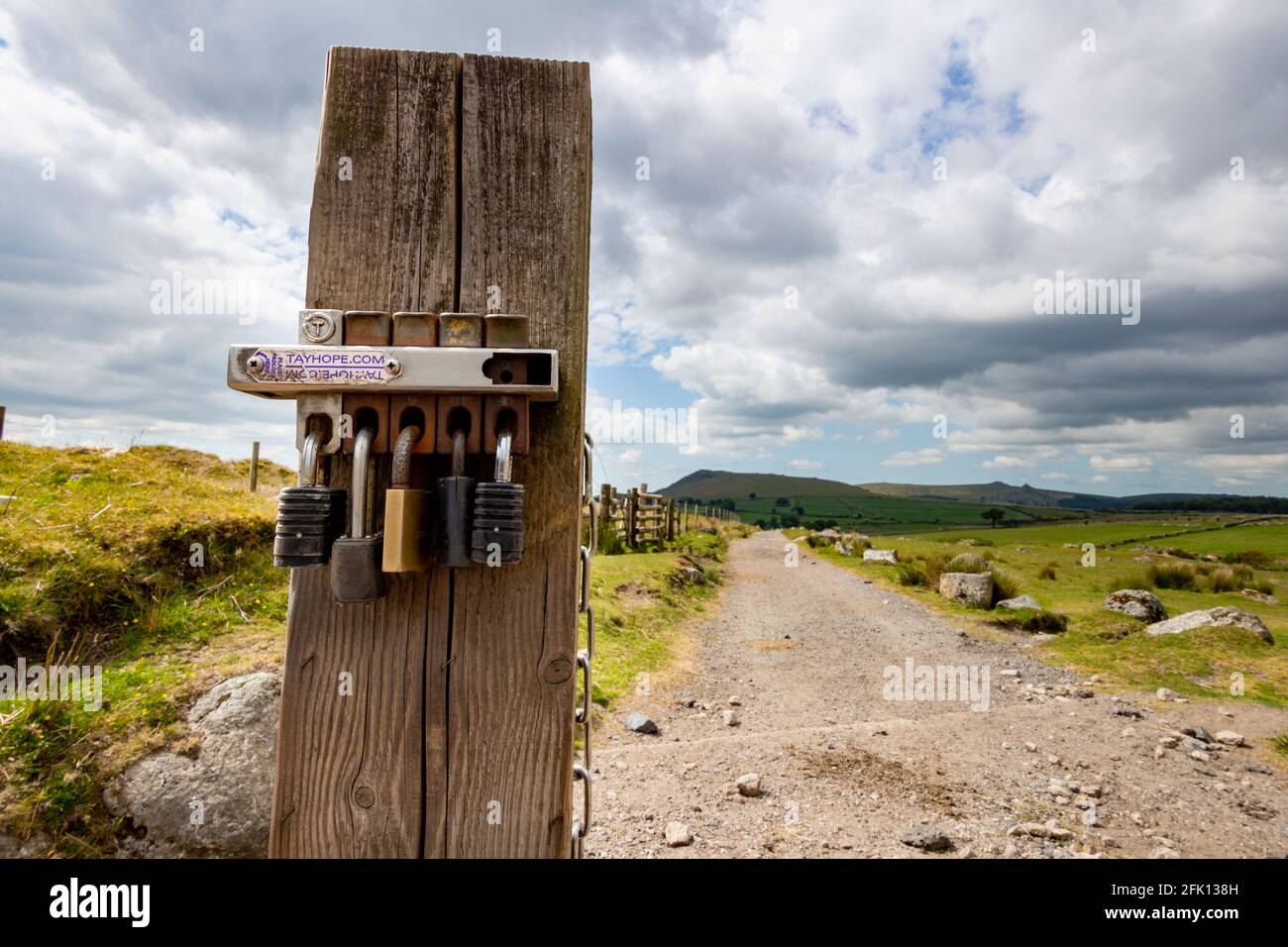 Five padlock hang on a open gate post with Dartmoor National Park and ...