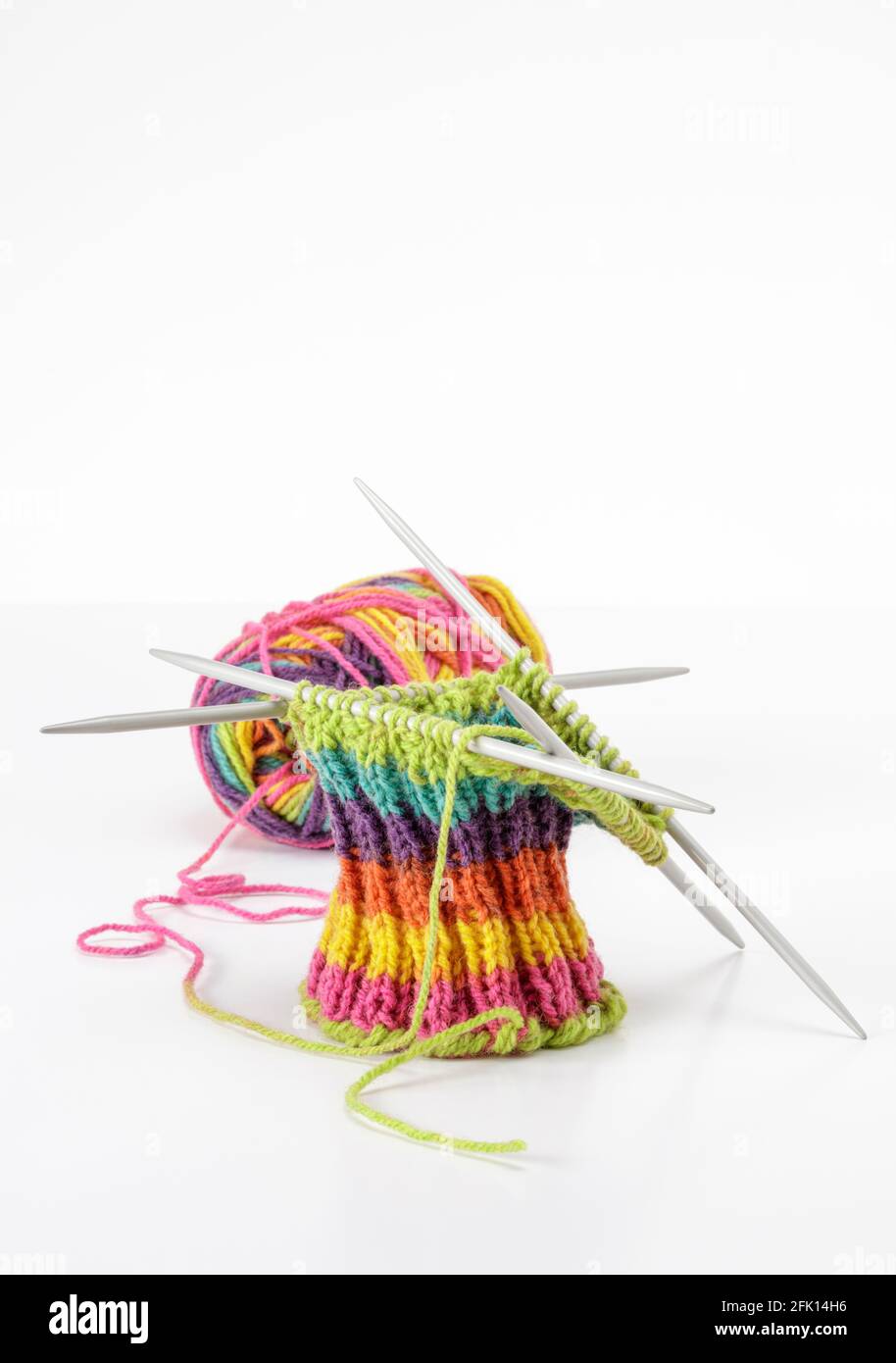 Multi coloured wool with knitting on white background Stock Photo - Alamy