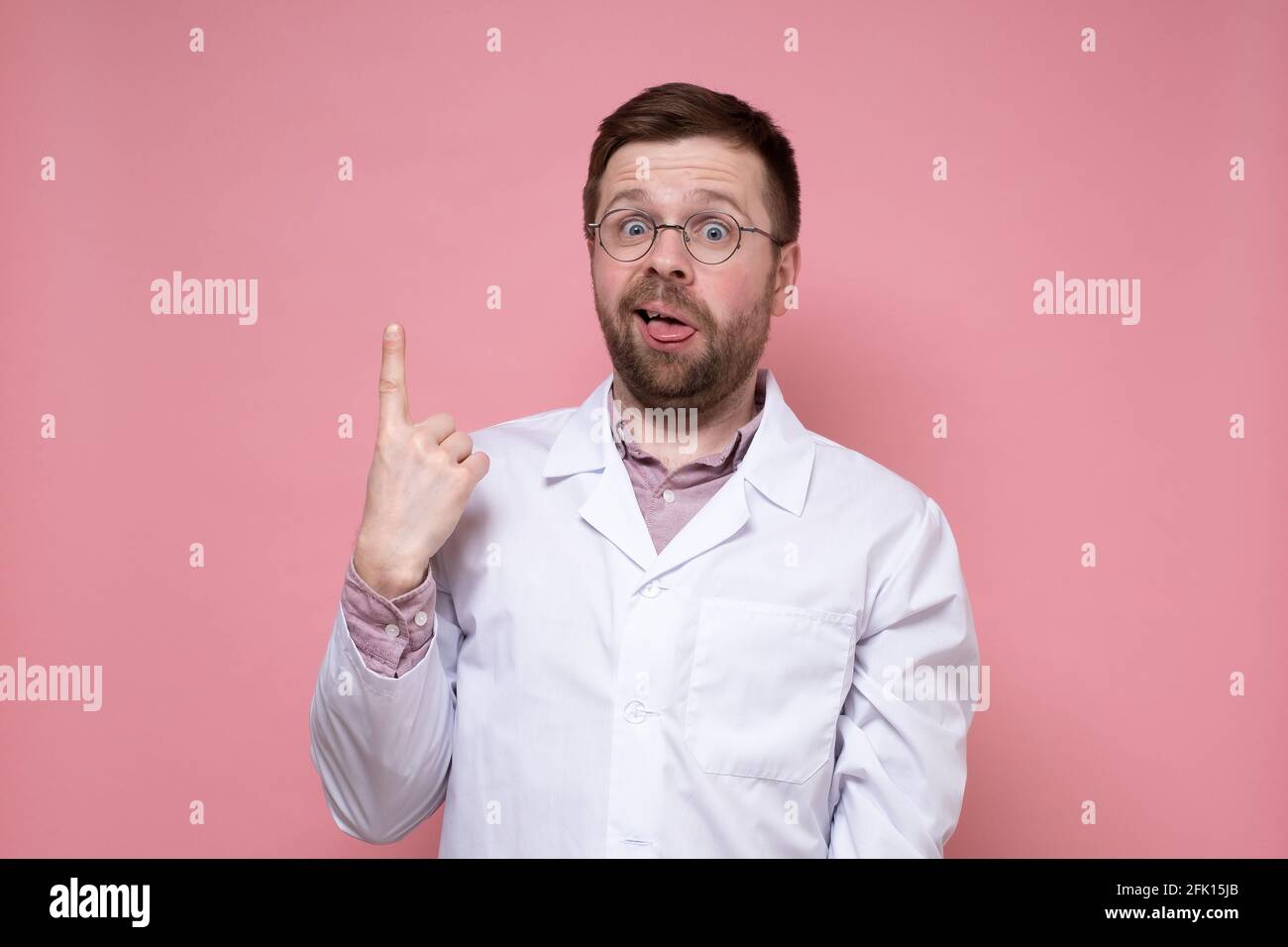 Puzzled doctor in glasses and a white coat points up with index finger ...