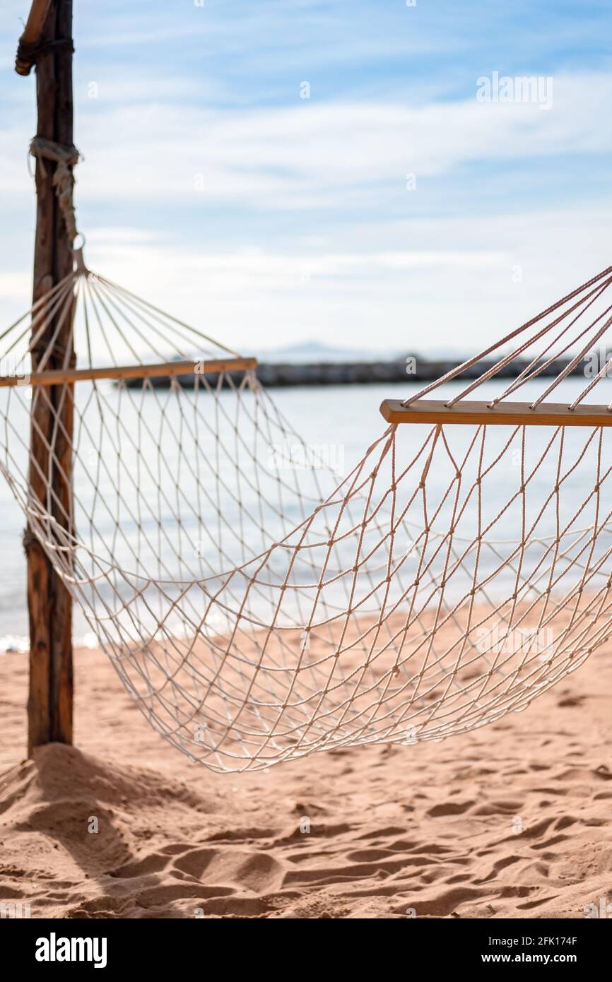 Rope hammock hanging on tropical beach, sea and sky are blurred ...