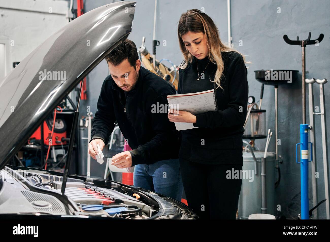 Two mechanics help each other in the work of a garage Stock Photo - Alamy