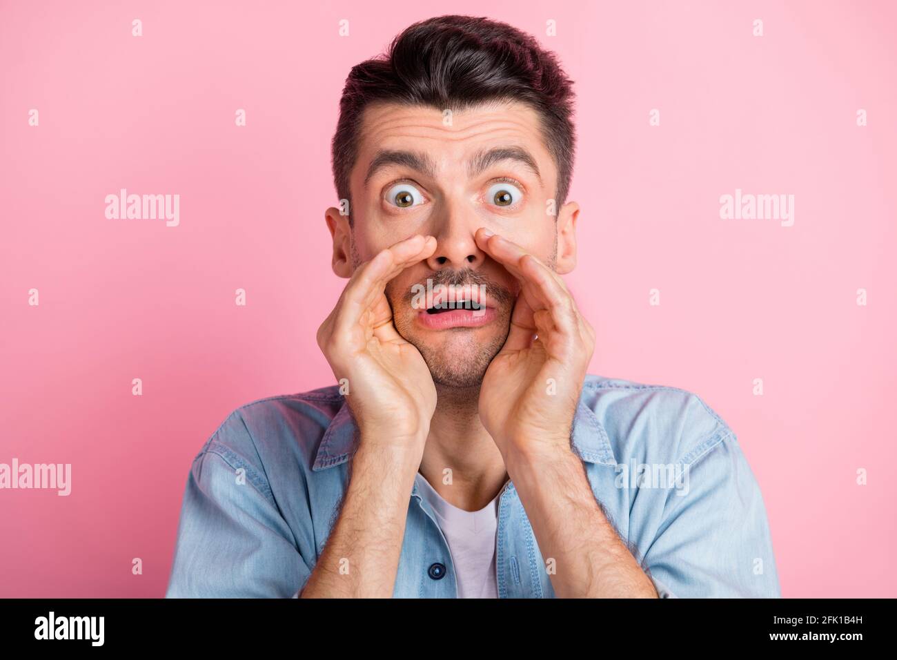 Photo of scared shocked brown haired young man hold hands mouth whisper ...