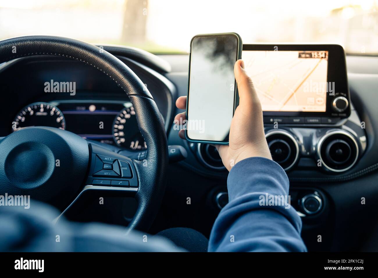 Teen drive a car and use smartphone. Young man reading messages holding ...
