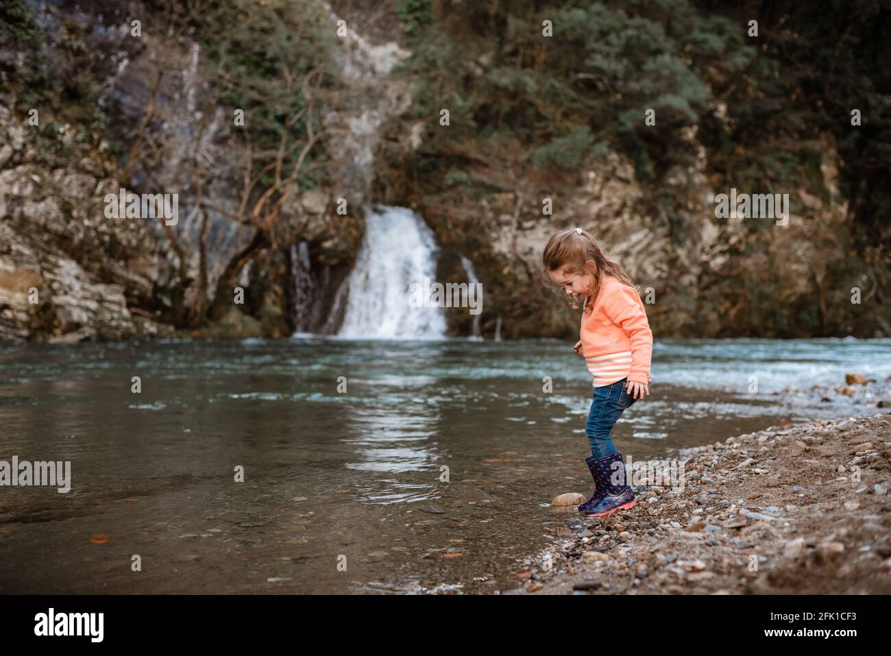 Small girl paddles by river in front of waterfall Stock Photo - Alamy