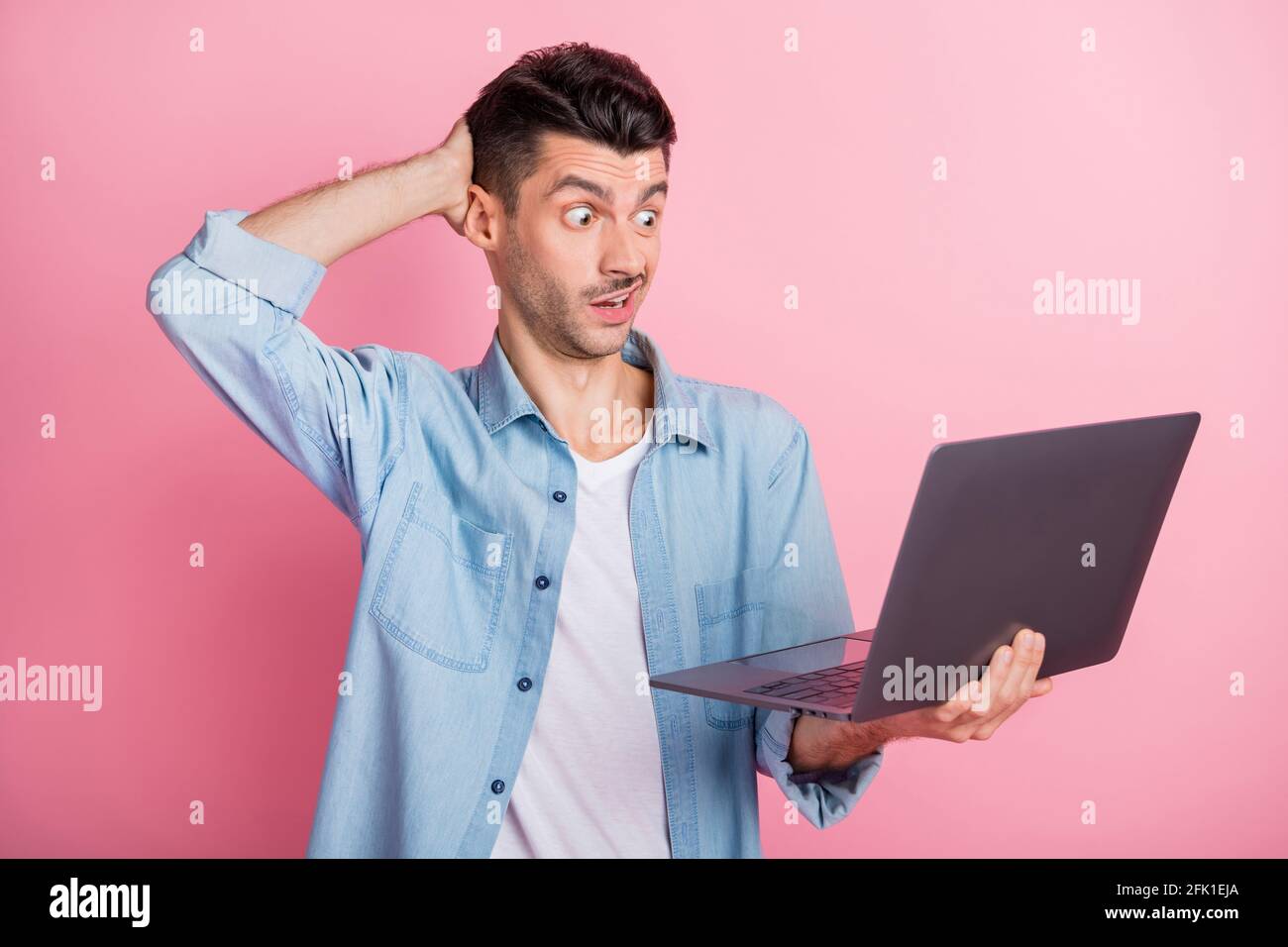 Photo of amazed handsome confused young man hold hand head laptop ...