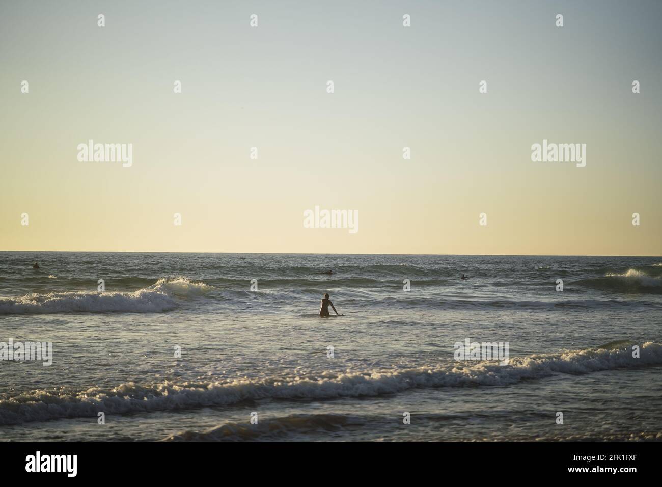 Scenic view of a woman enjoying the waves at a beach under a clear sky ...