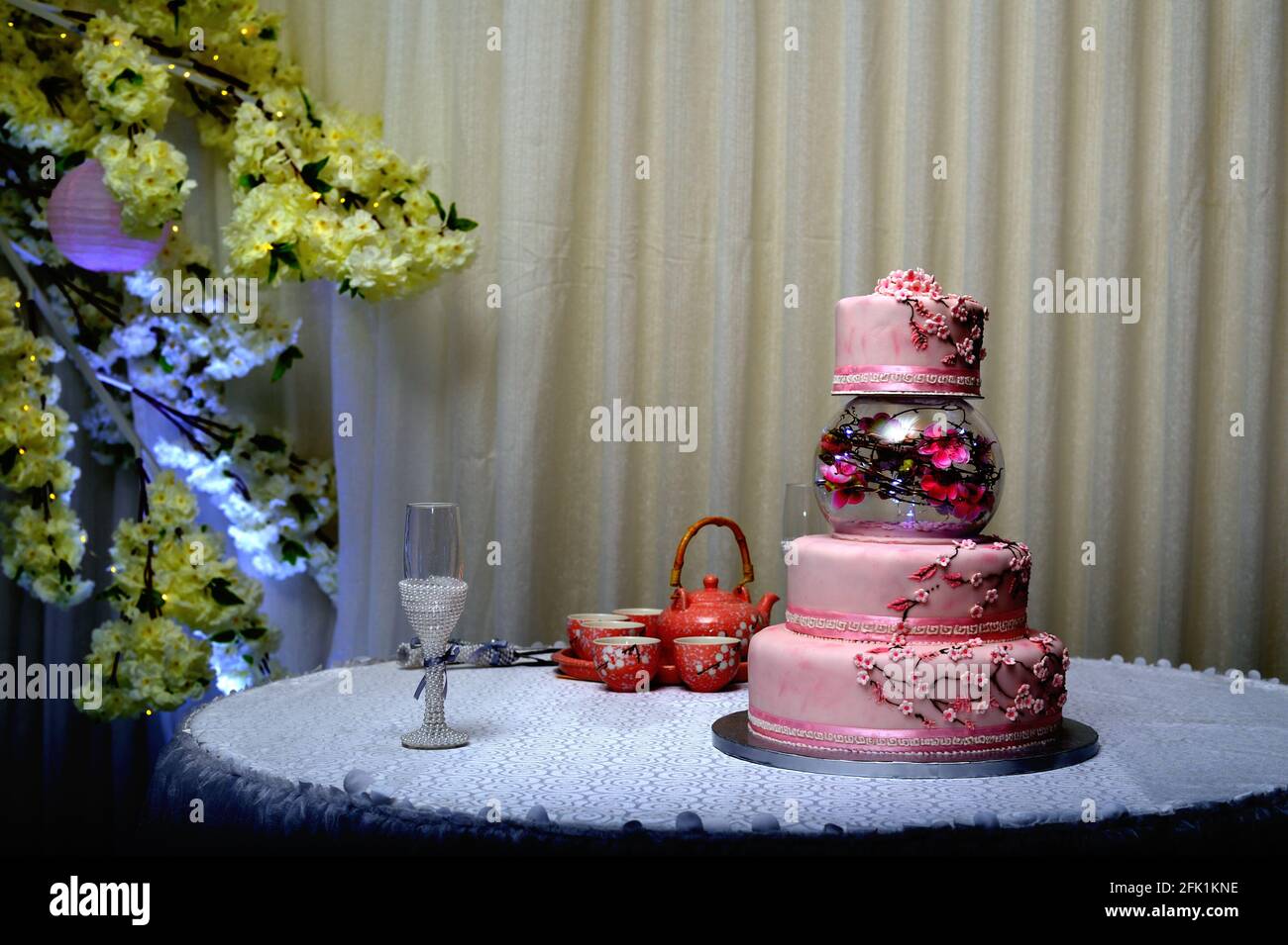 Tall wedding cake with glass and and porcelain tea set sitting next to ...