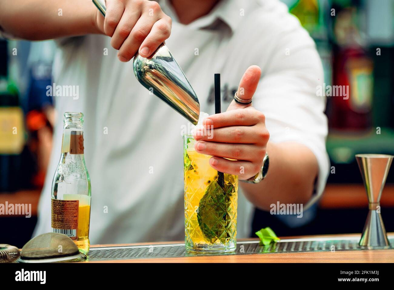 The bartender pours ice into a yellow cocktail Stock Photo - Alamy