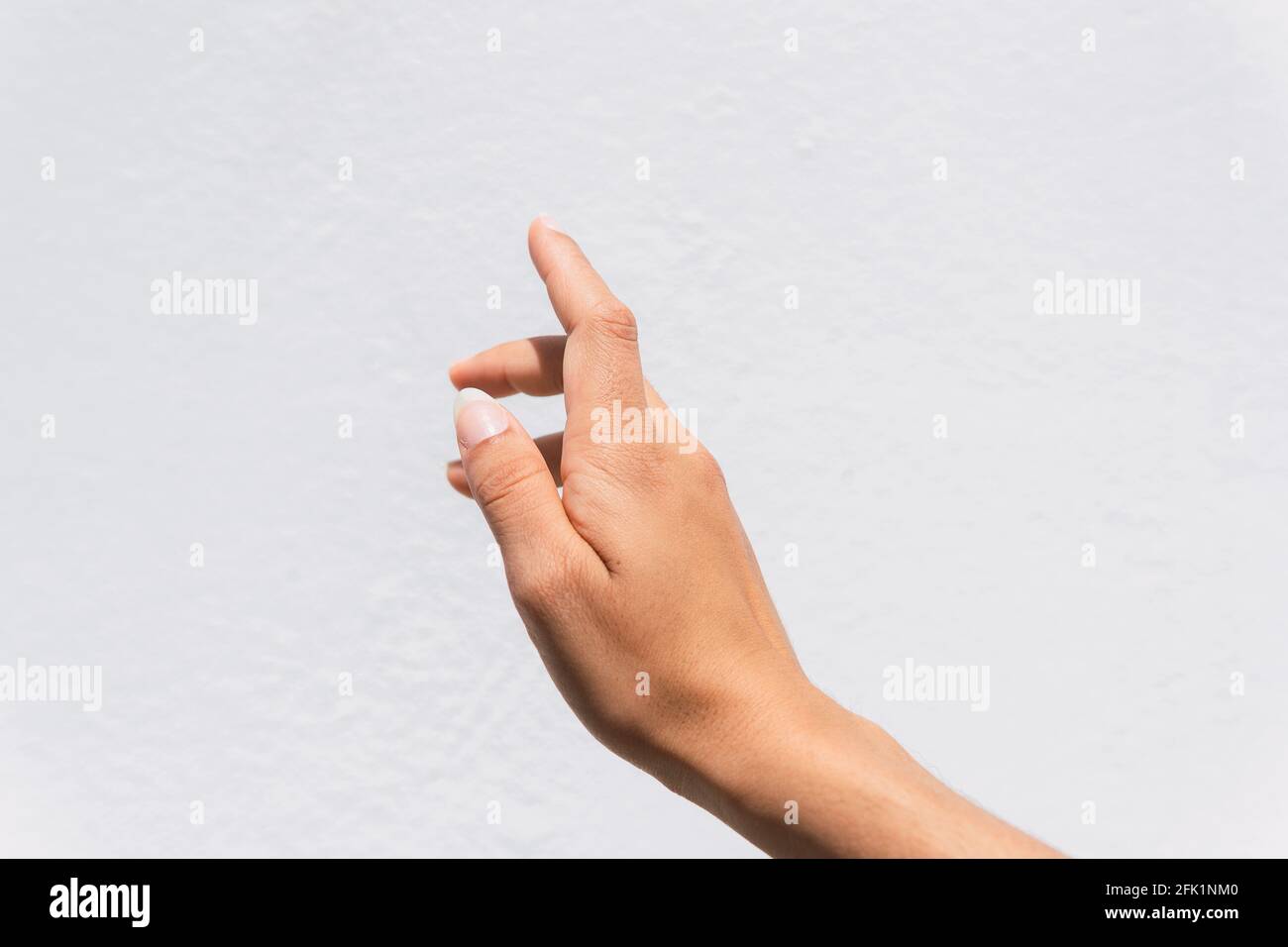 Closeup of reaching out hand sign against a white wall background Stock ...