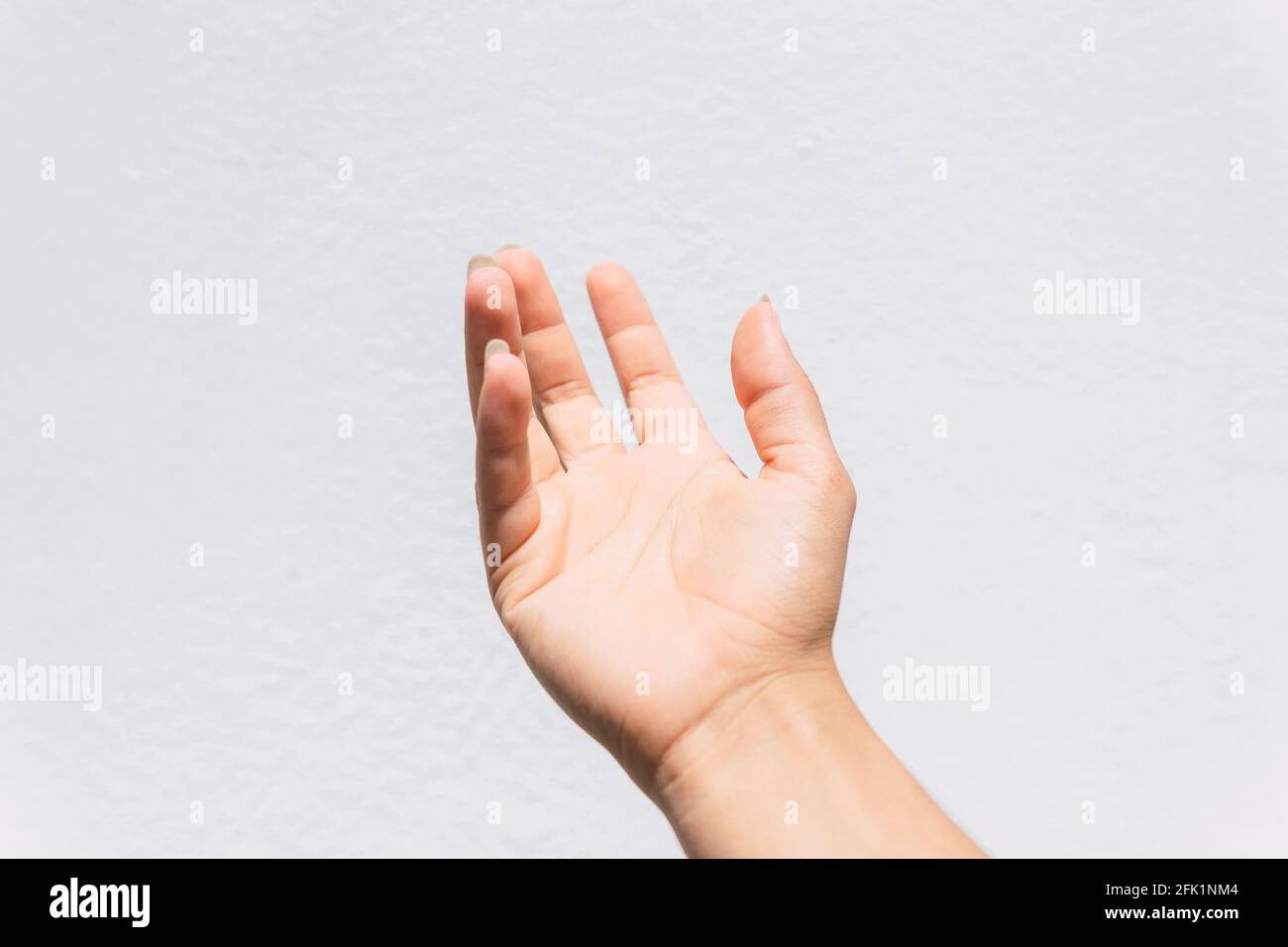 Closeup of asking hand sign against a white wall background Stock Photo ...