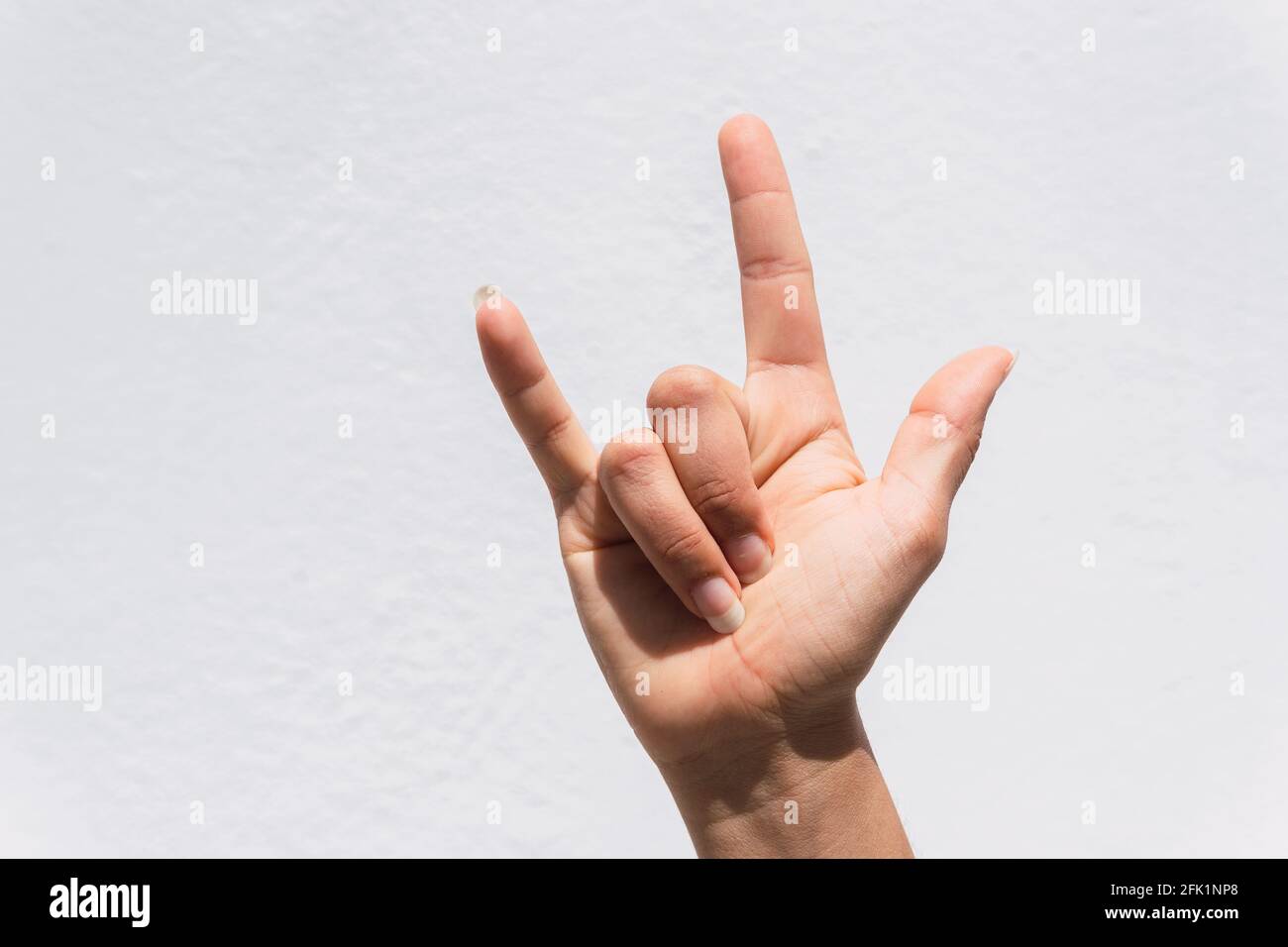 Closeup of the ILY hand sign against a white wall background Stock ...