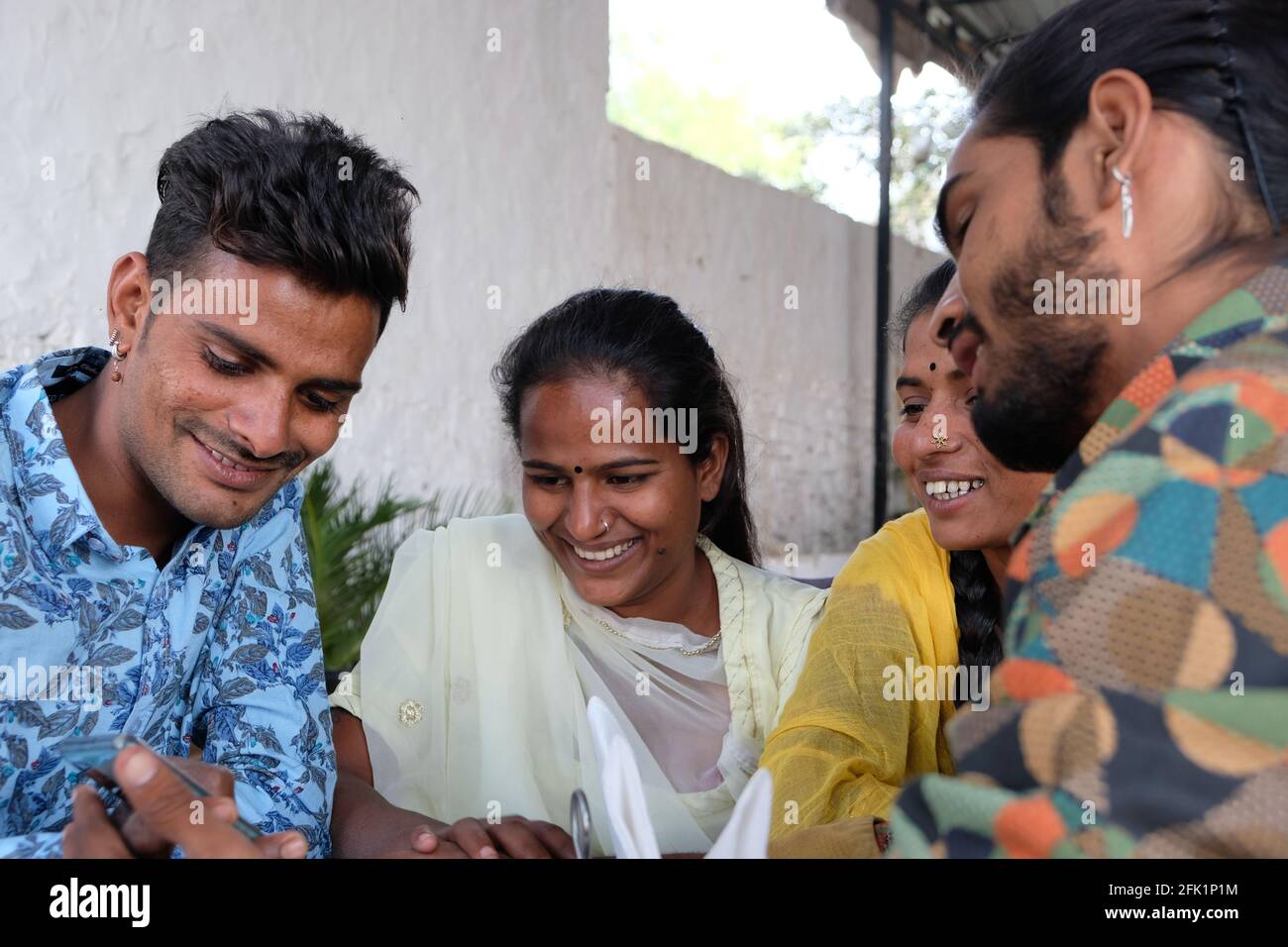 Group of happy young Indian friends having fun in a cafe looking at the ...
