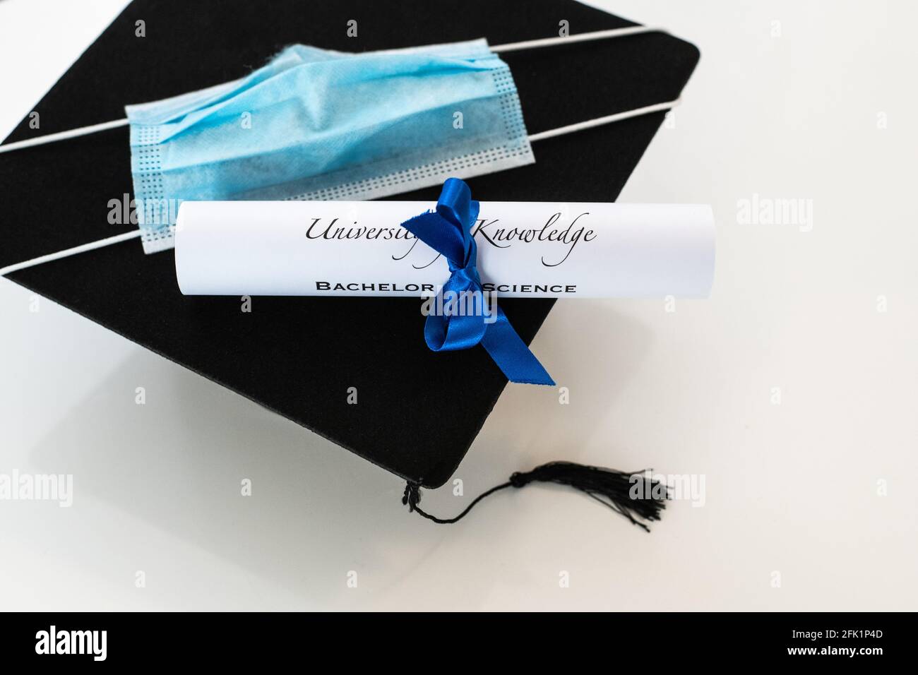 Closeup of graduation hat with degree and surgical mask on white ...