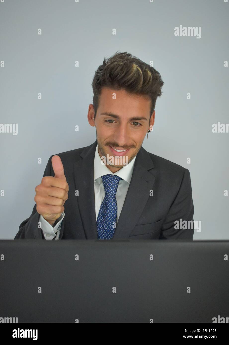 Young Spanish man showing a thumbs up sign during an online meeting ...