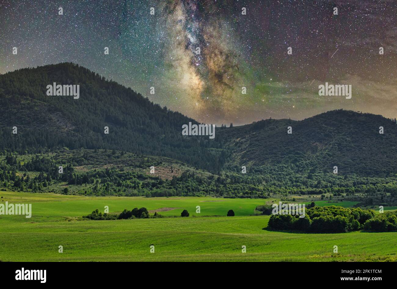 Milky Way in a starry night sky above forested mountains Stock Photo ...
