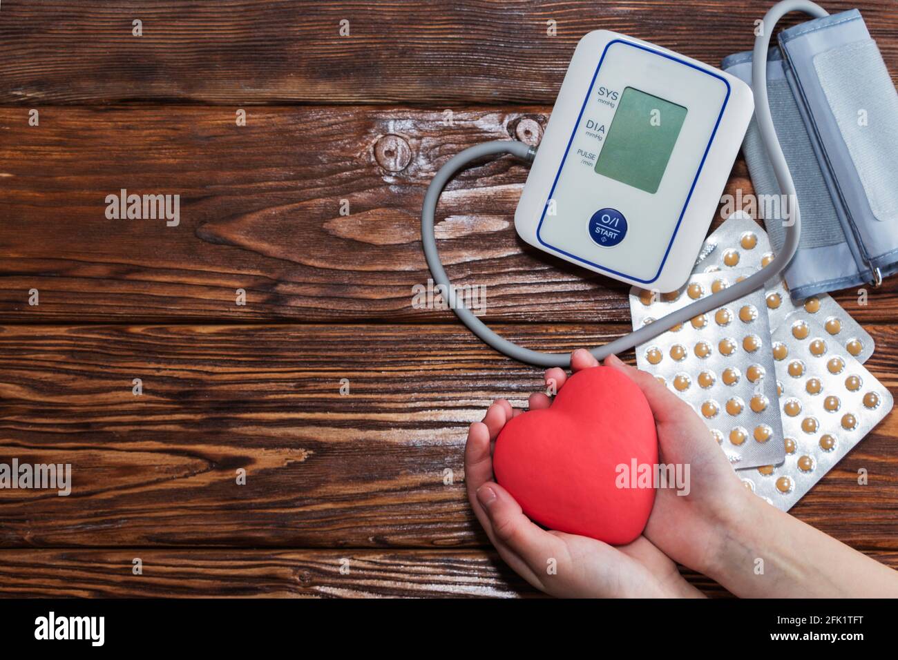 White electric tonometer, red heart and pills, on wooden table Stock ...