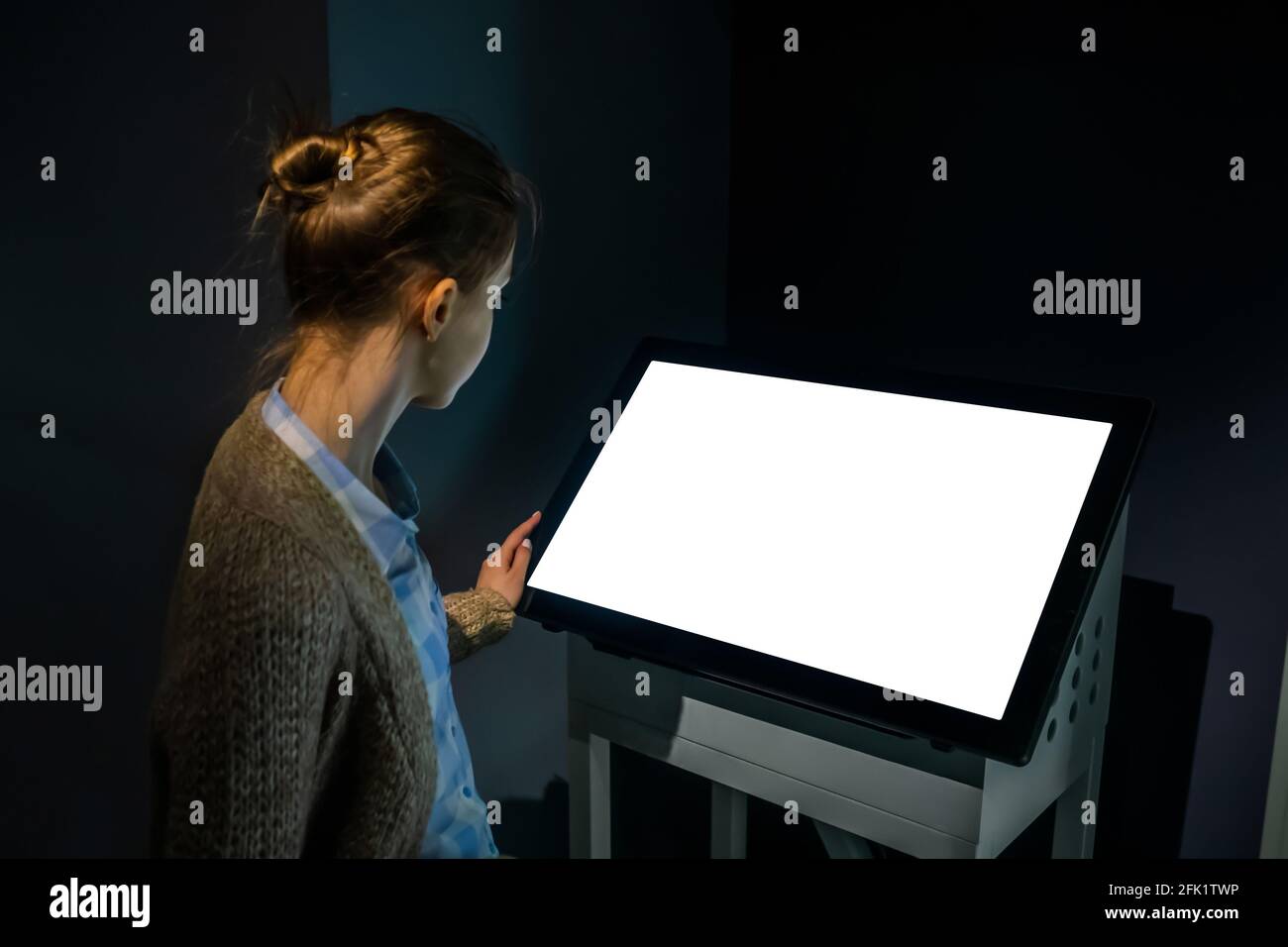Woman using interactive empty white touchscreen display kiosk at ...