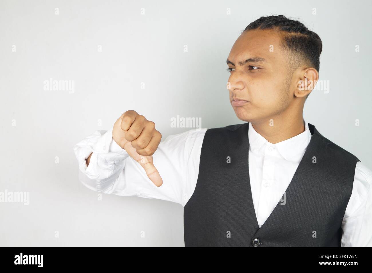 Handsome Indian man in formal wear displeased with the thumbs down ...
