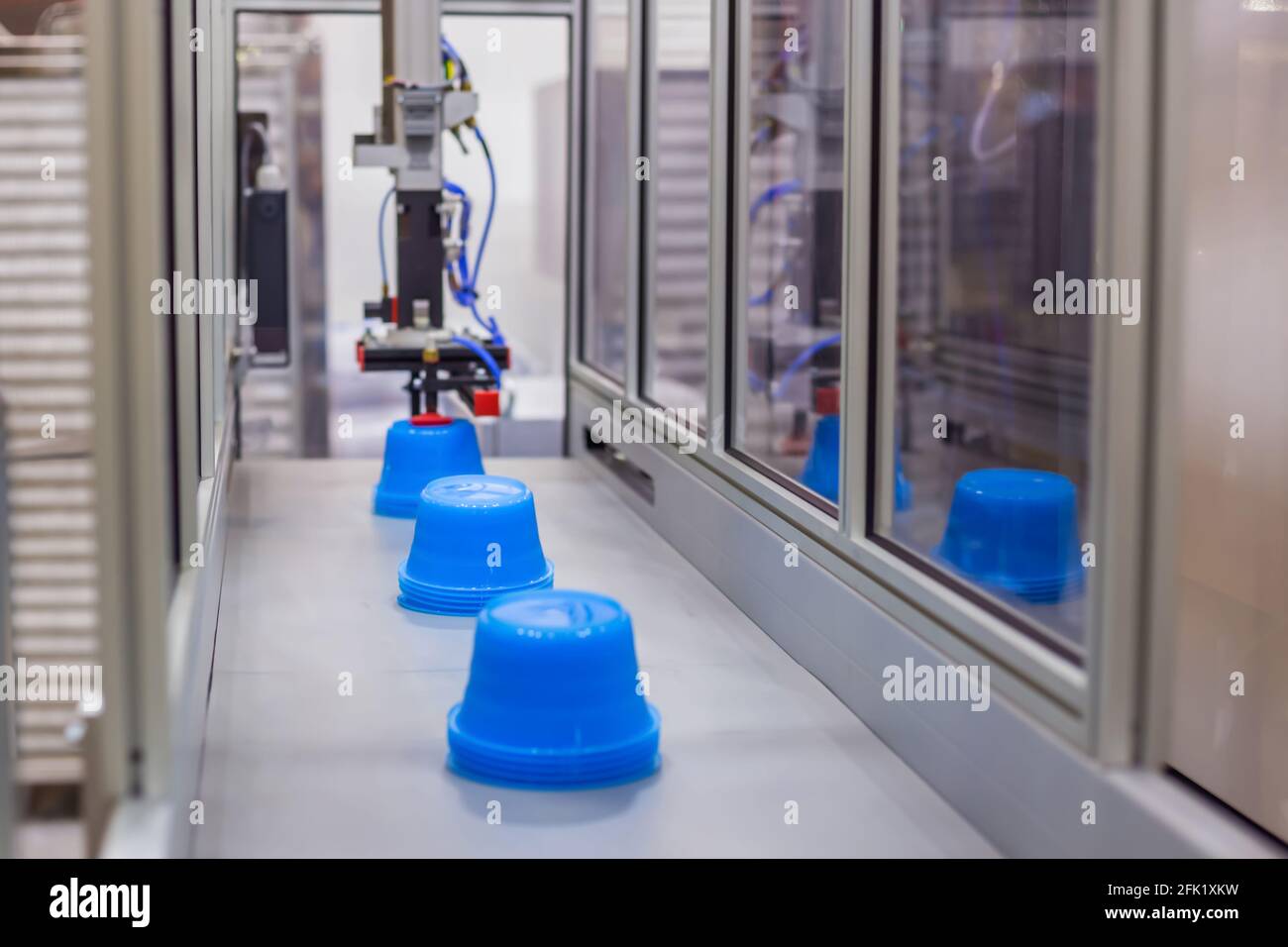 Pots on conveyor belt of plastic injection molding machine with robotic ...