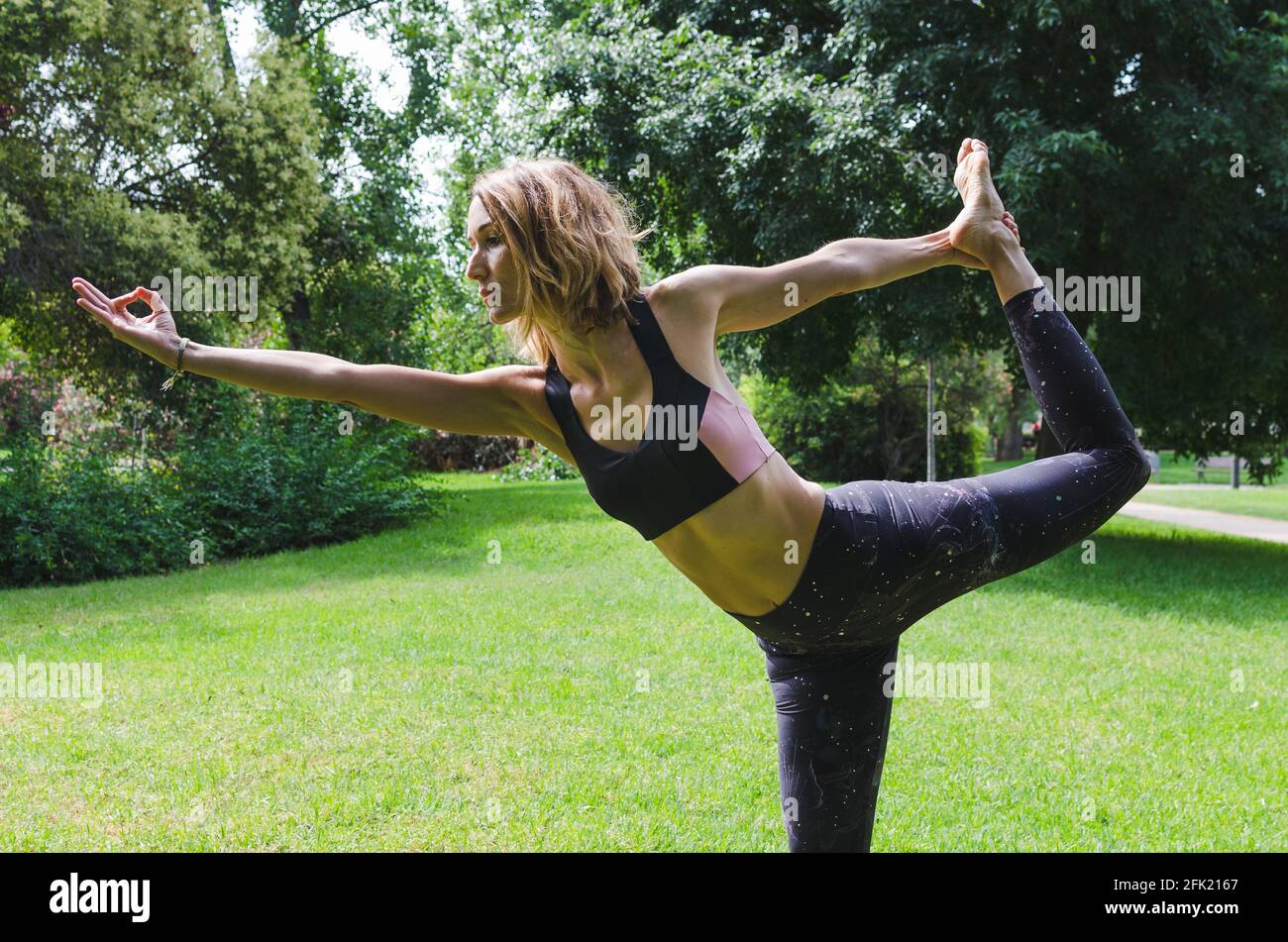 girl doing yoga in the park. side view. Lord of the dance pose Stock ...