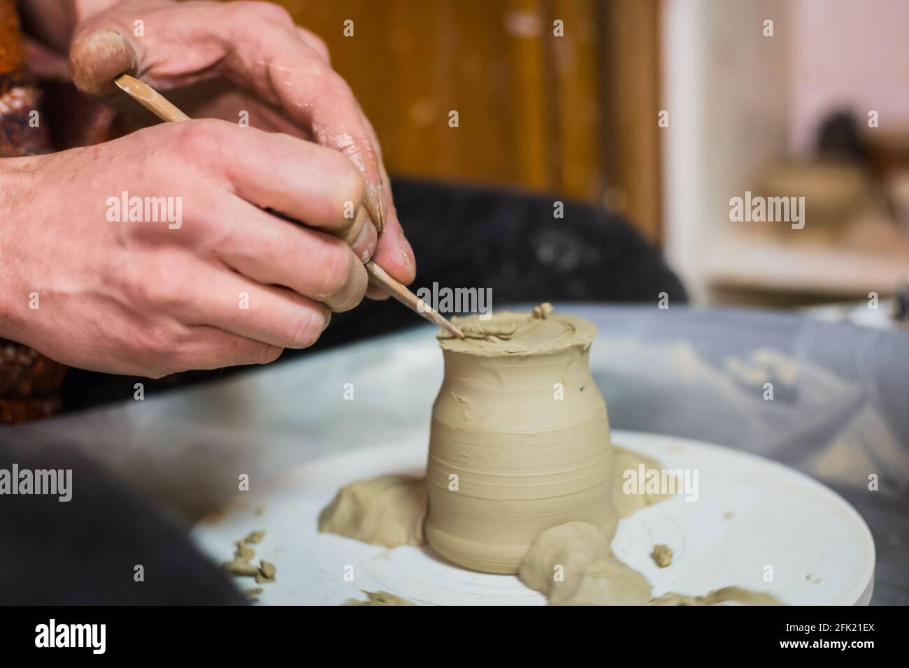 Professional potter shaping mug with special tool in pottery workshop ...