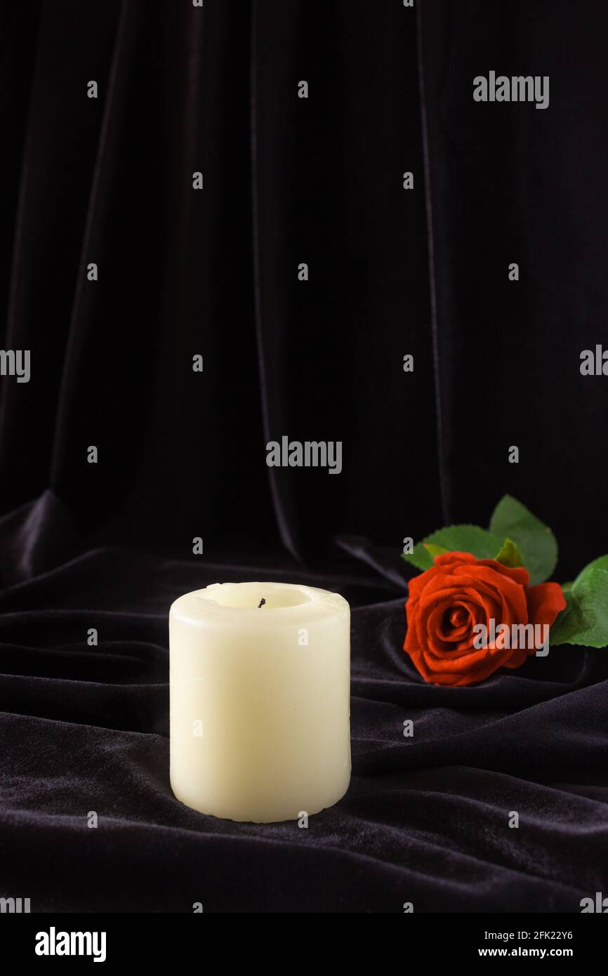 An extinguished candle and a red rose on a black background. The ...