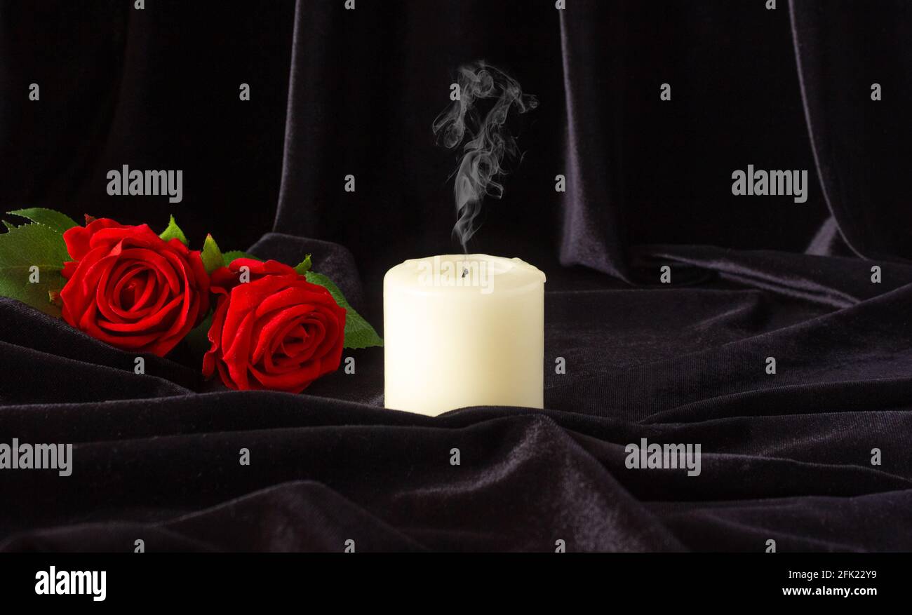 An extinguished candle and a red rose on a black background. The ...