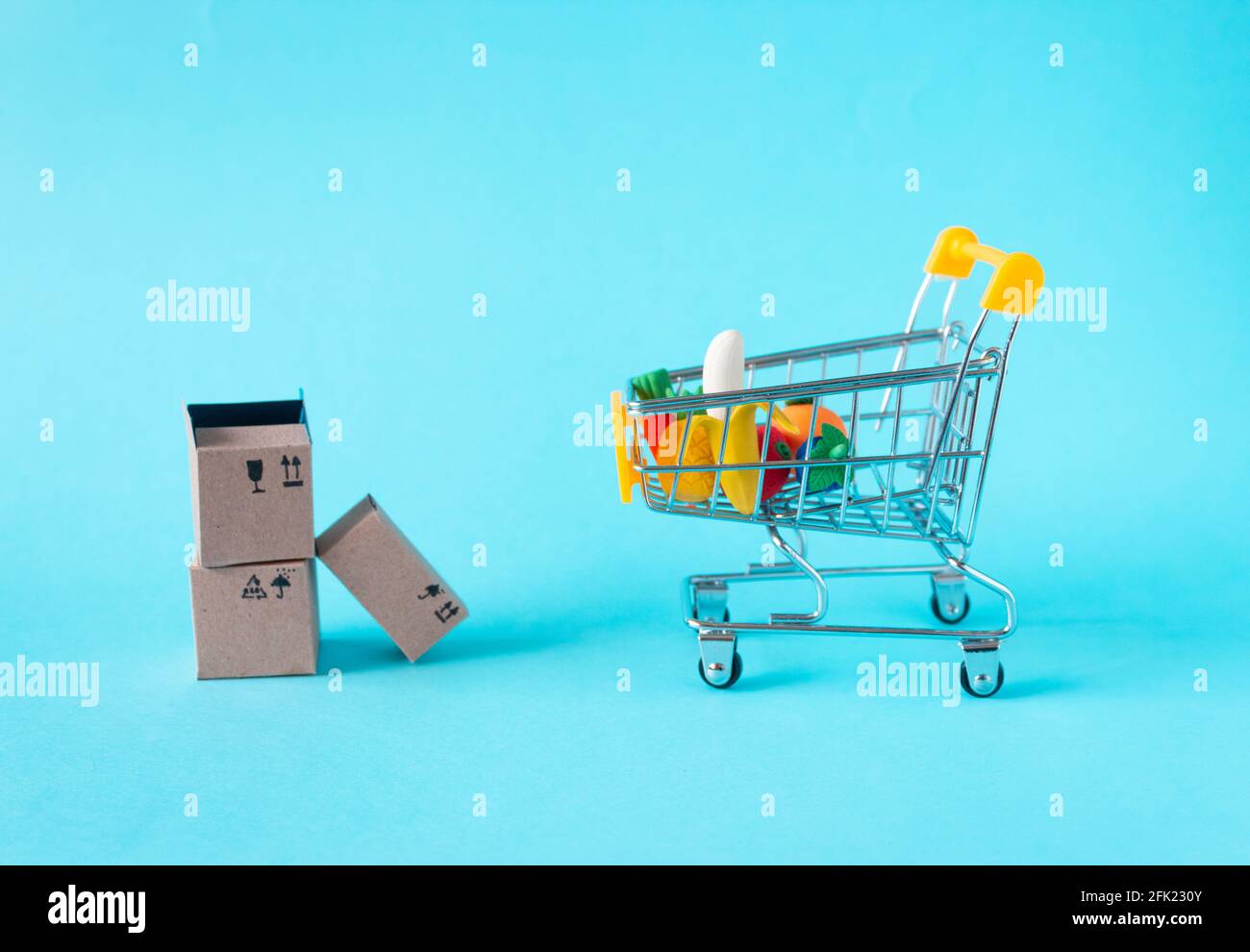 A small grocery cart with fruit and boxes of goods on a blue background ...