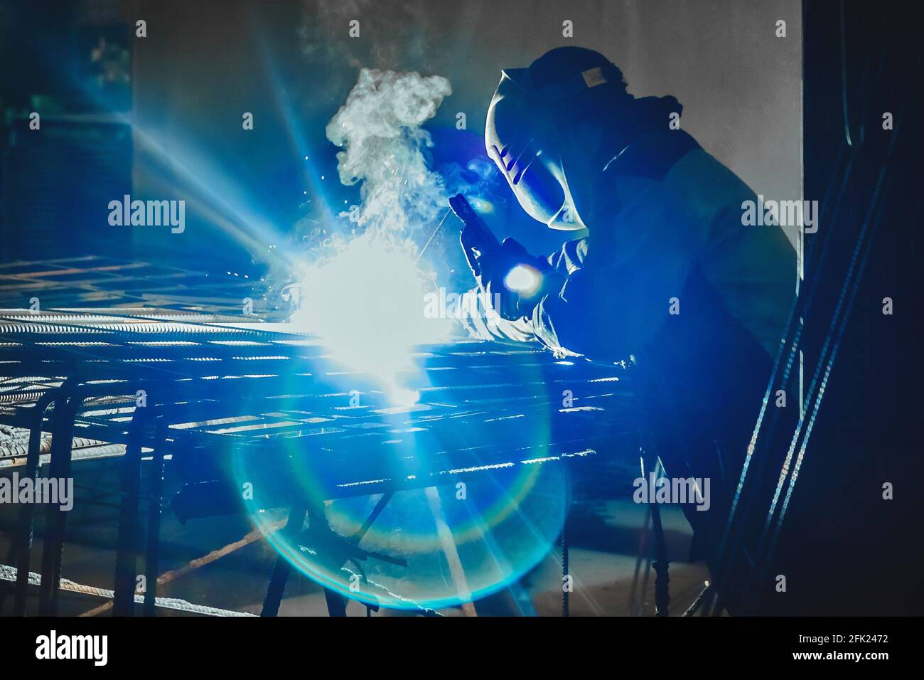 Working man is doing welding work on metal structures in a factory or ...