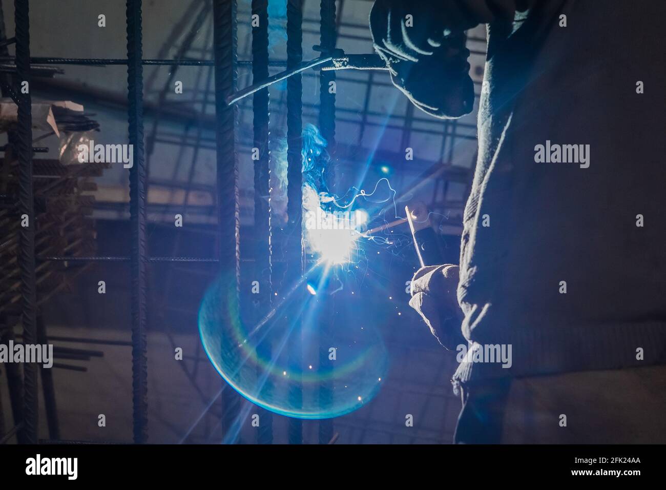 Working man is doing welding work on metal structures in a factory or ...