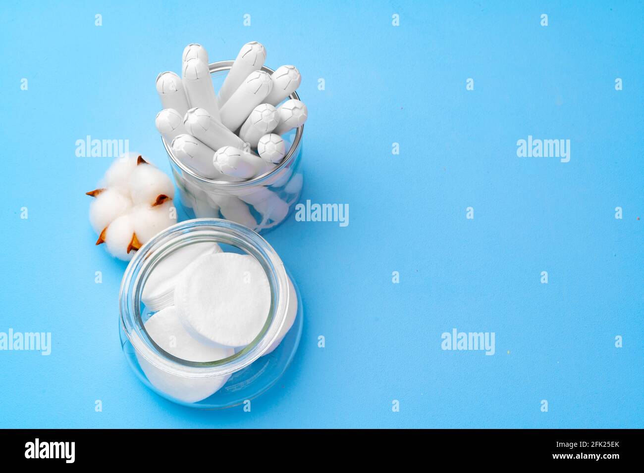 Female medical tampons and cotton flower on blue paper background Stock ...