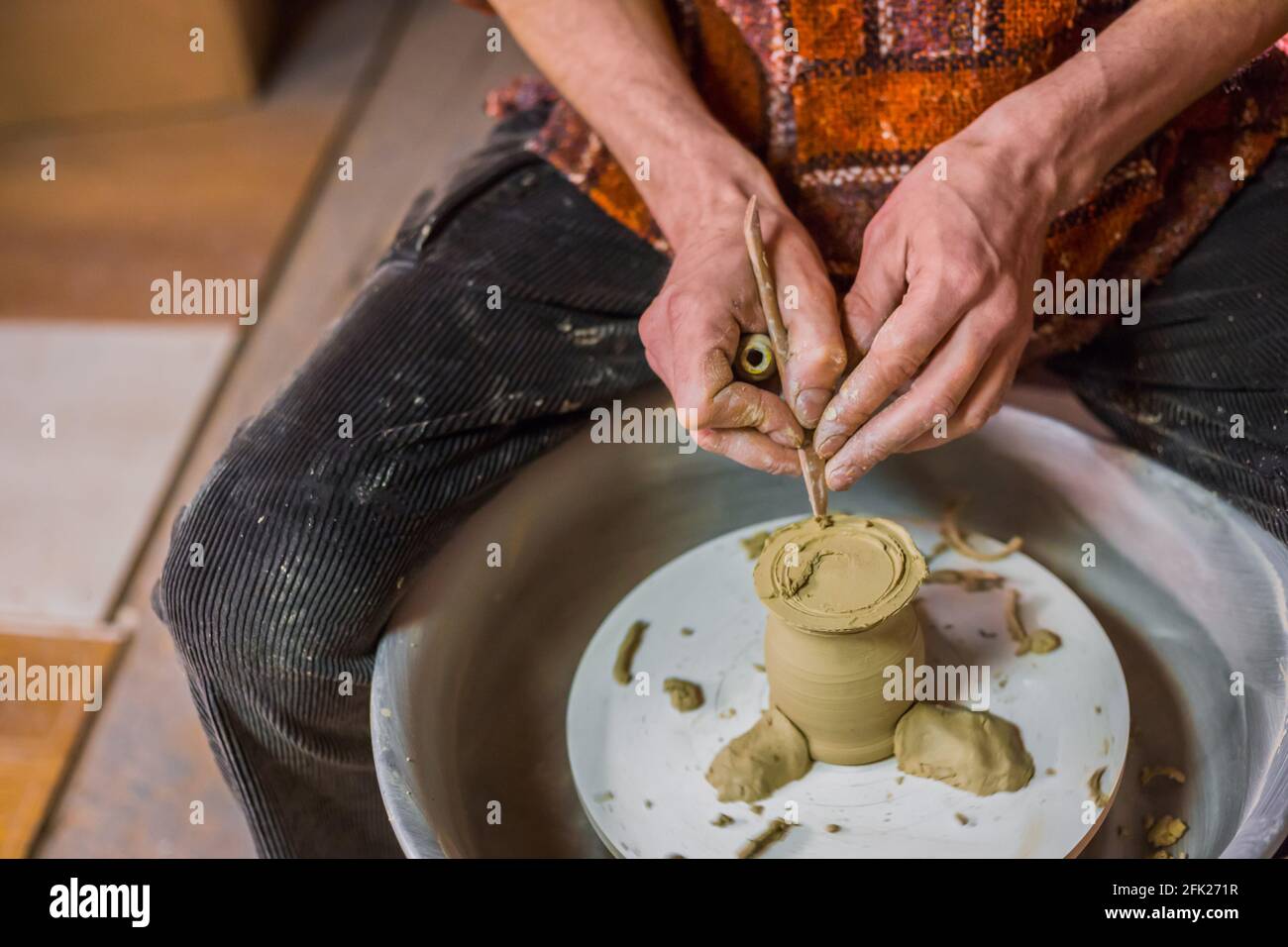 Professional potter shaping mug with special tool in pottery workshop ...