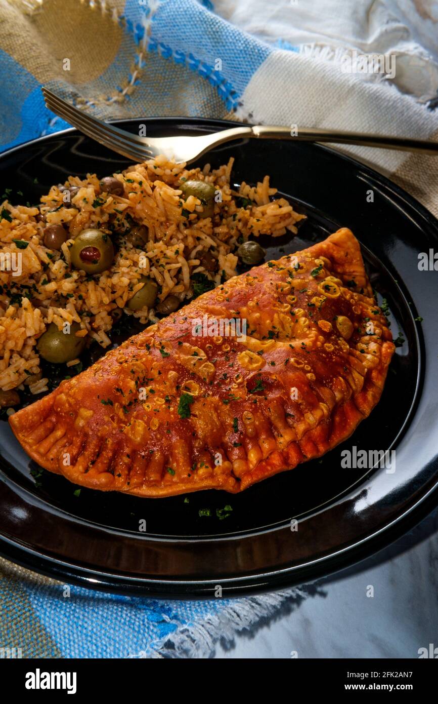 Mexican fried empanada meat pies with olive caper rice Stock Photo - Alamy